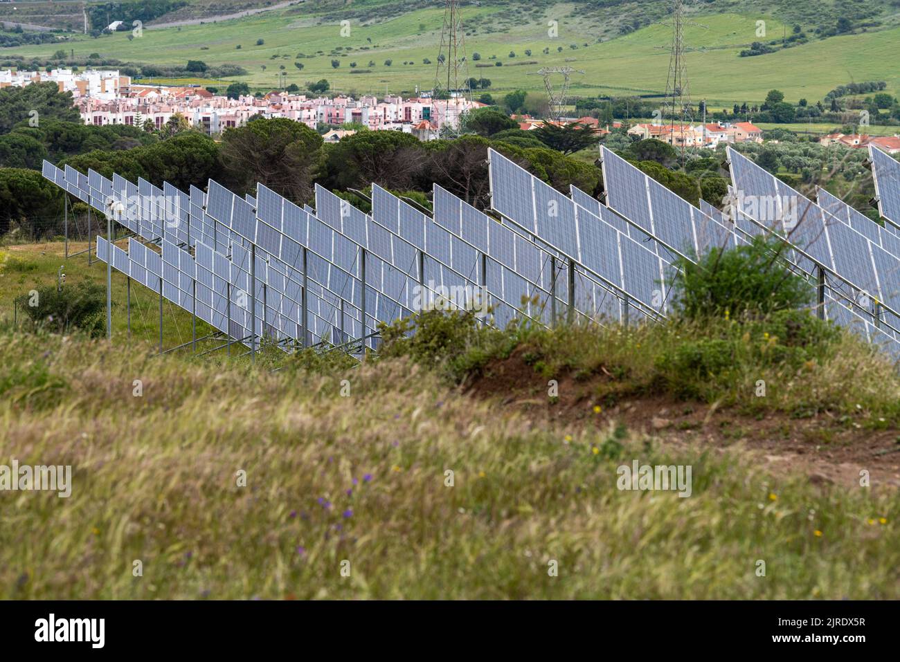 A shot of a huge area with solar panels with town and fields around ...