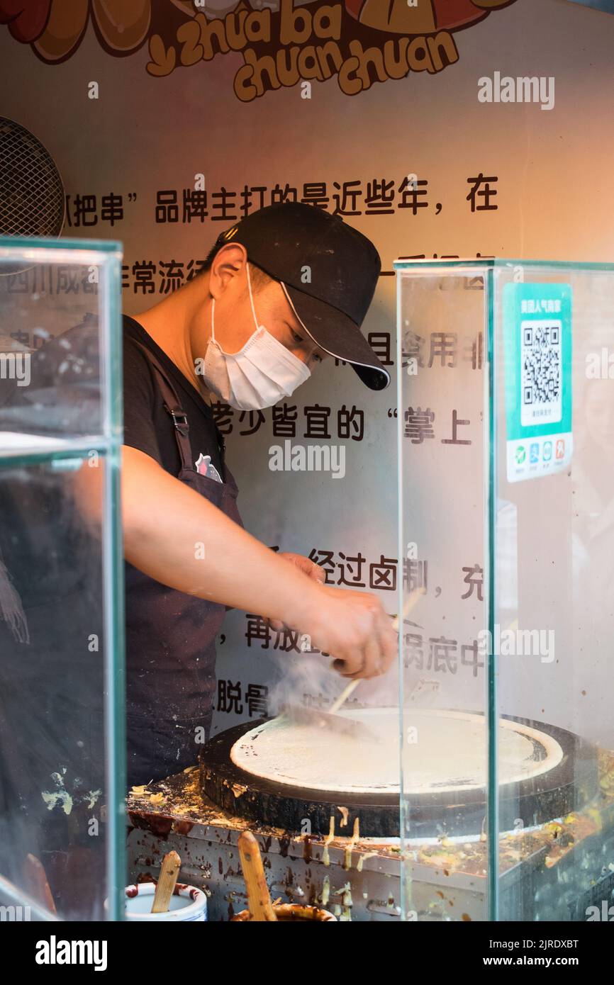 Man wearing a mask against pollution making Chinese pancake called ...