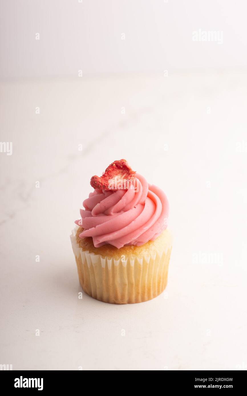 A vertical shot of a vanilla cupcake with strawberry cream isolated on ...