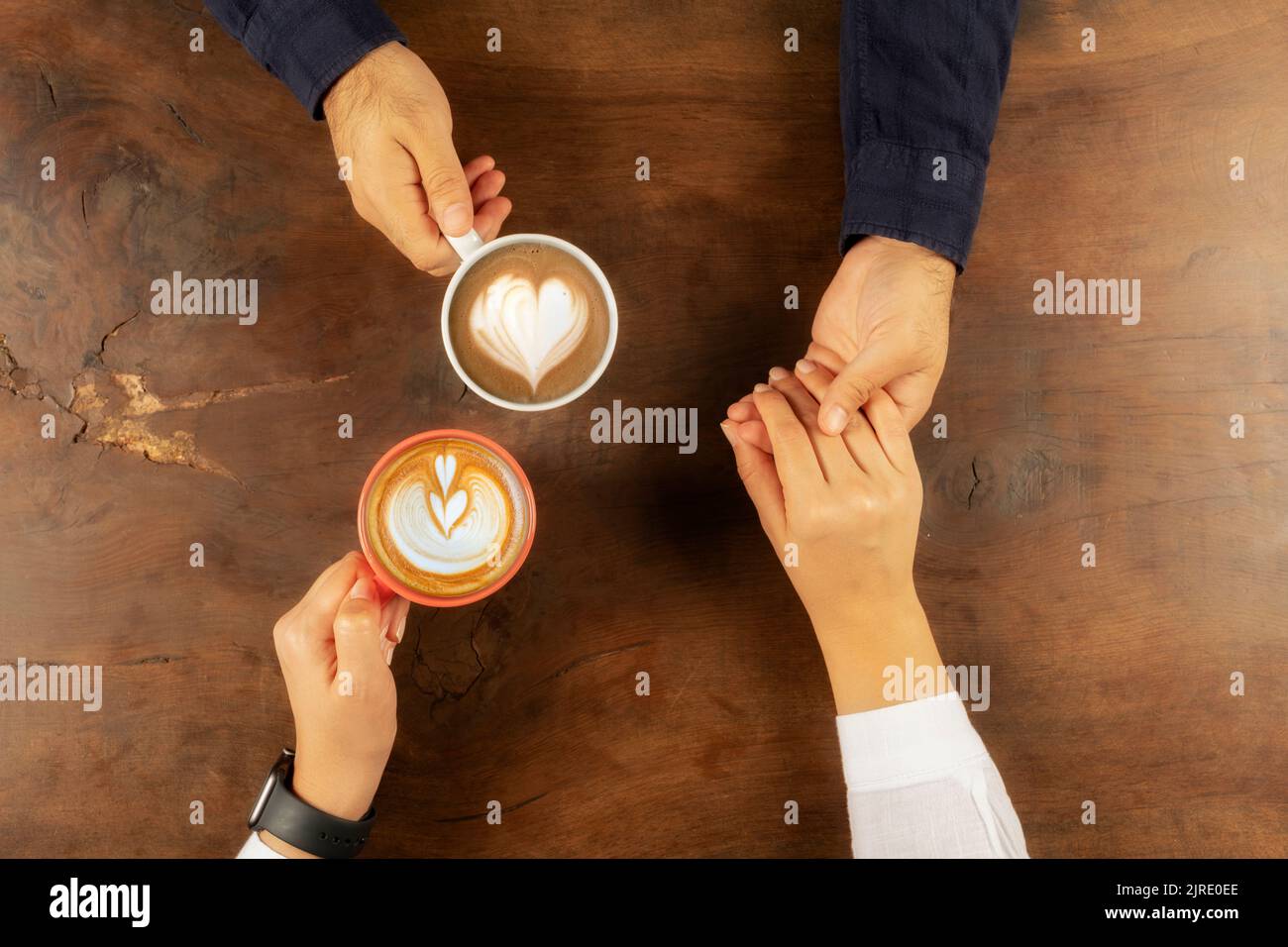 Holding hands, top view photo of young lovers holding hands. Drinking ...