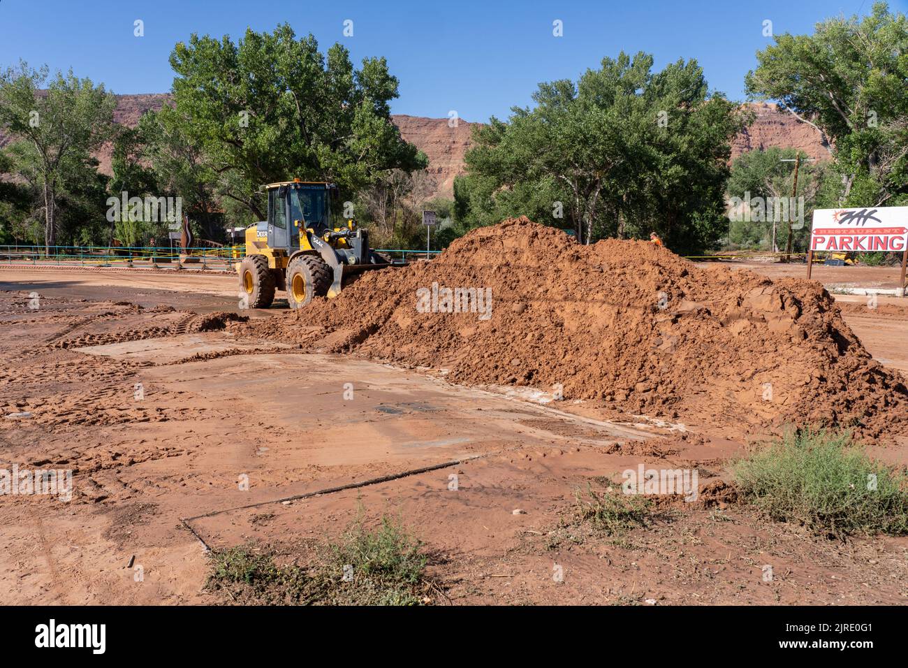 A front-end loader scrapes up mud off the street the day after a flash ...