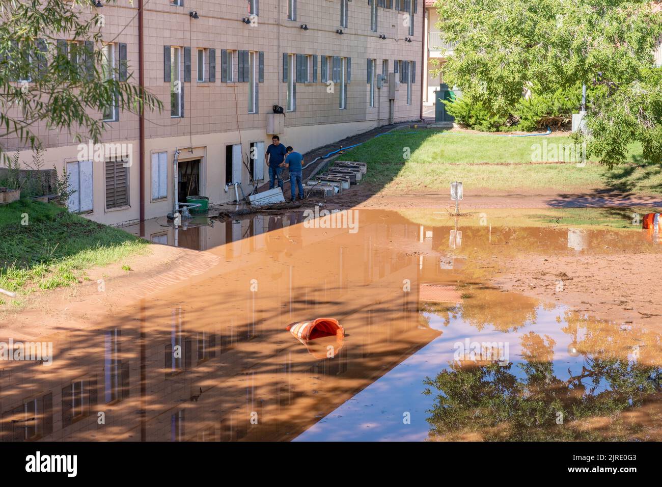 Workers remove equipment from a flooded storeroom at a motel in Moab ...