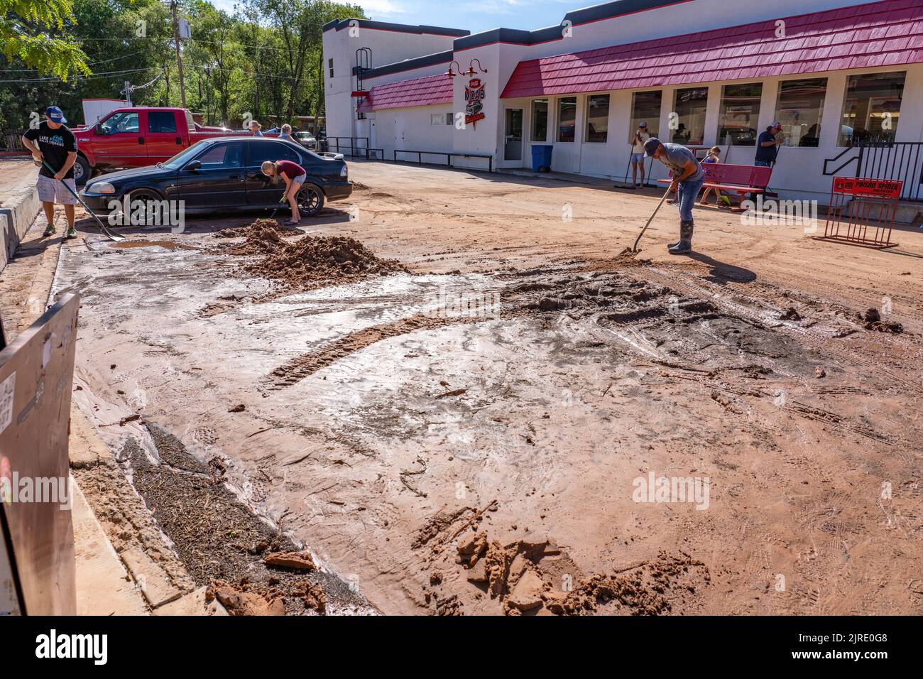 Volunteers shovel mud in the parking lot of a restaurant flooded the ...