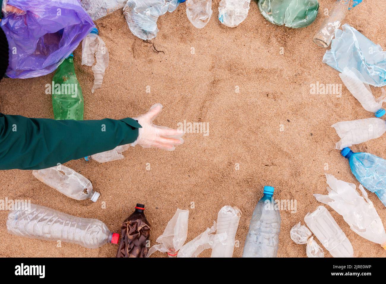 Volunteer picking up a garbage. Frame from plastic dirty bottles with ...