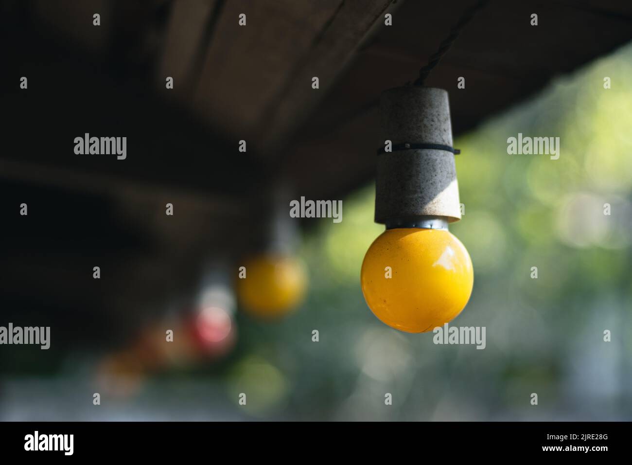Illuminated colorful bulbs hanging on wire on roof Stock Photo - Alamy