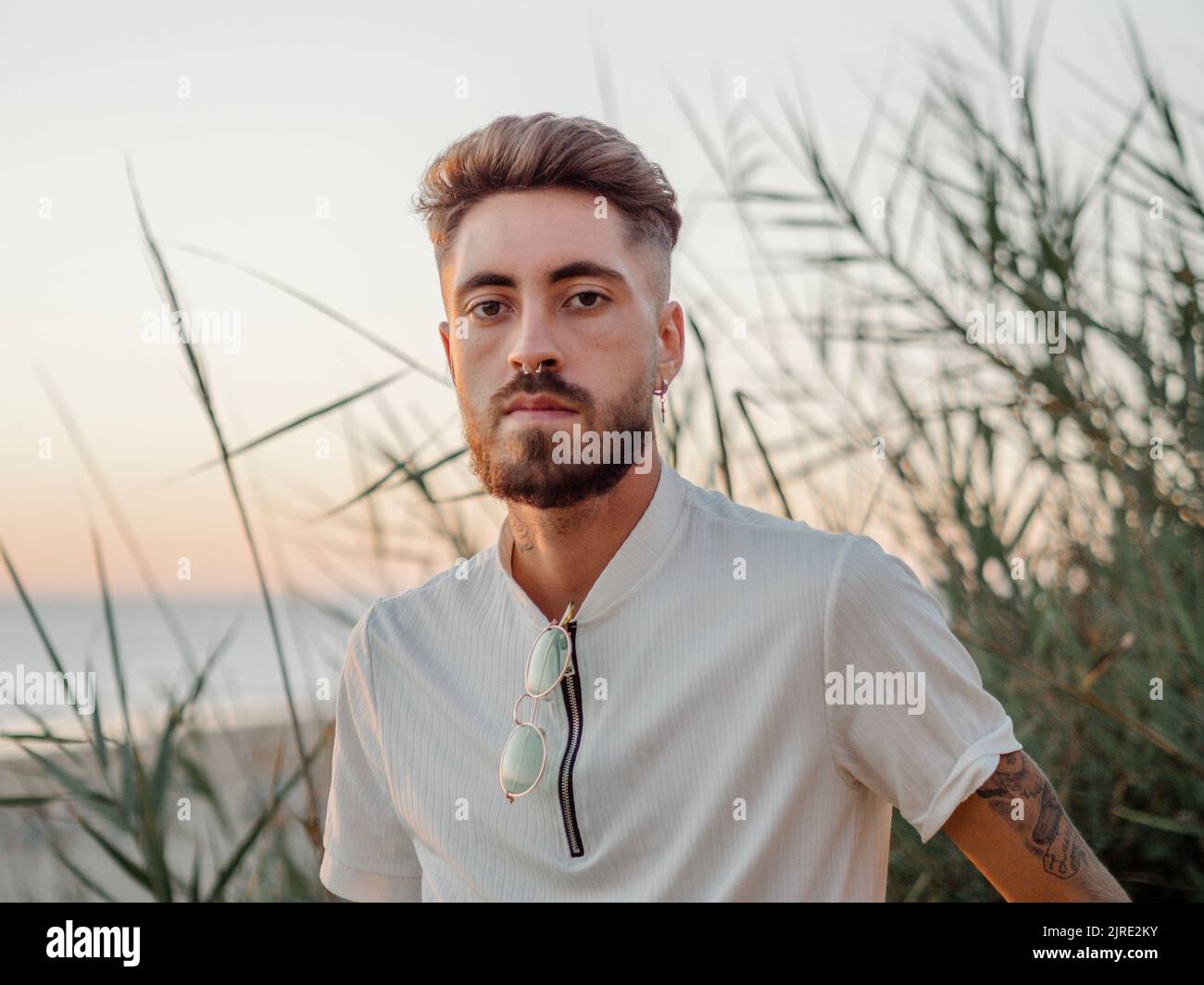 A portrait of a Caucasian guy with a beard and piercing, looking into ...