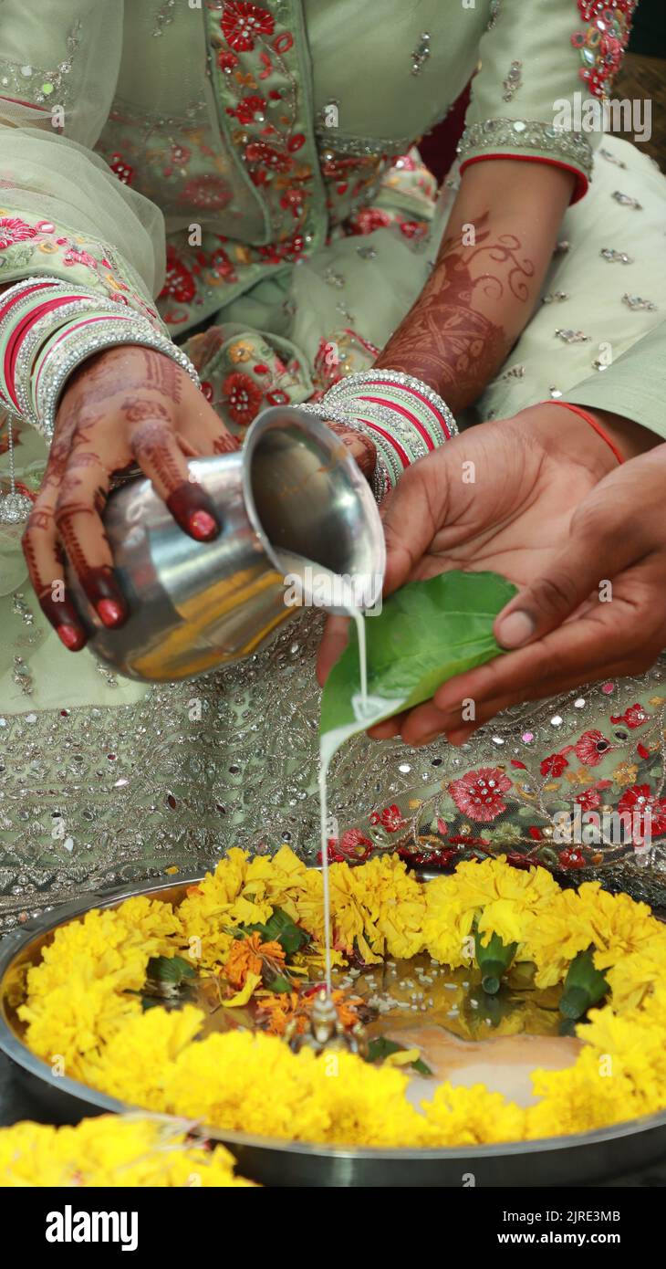 A bride holding a metal jar with milk in it and pouring milk down to a ...