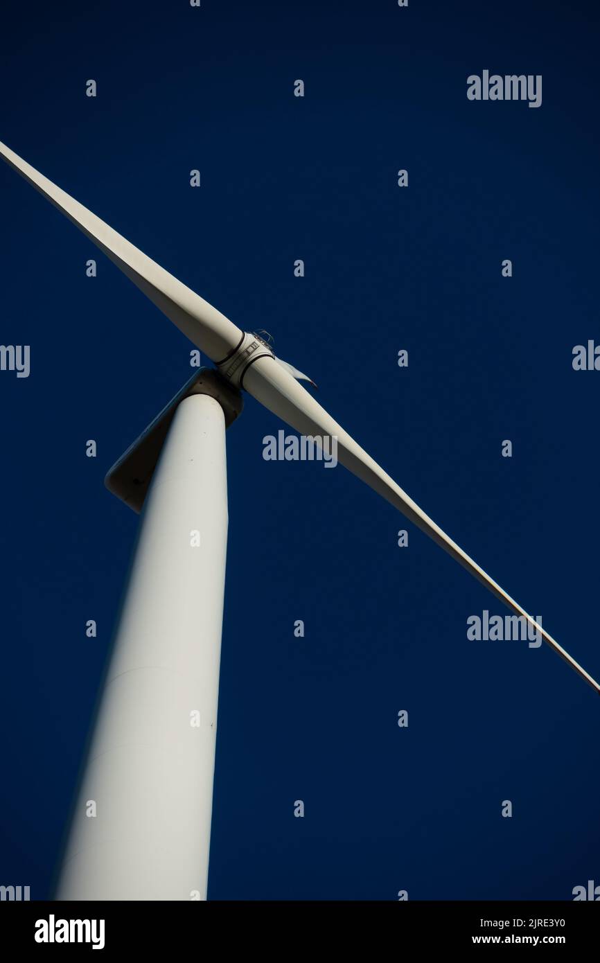 White blades of a wind turbine against the background of a navy blue ...