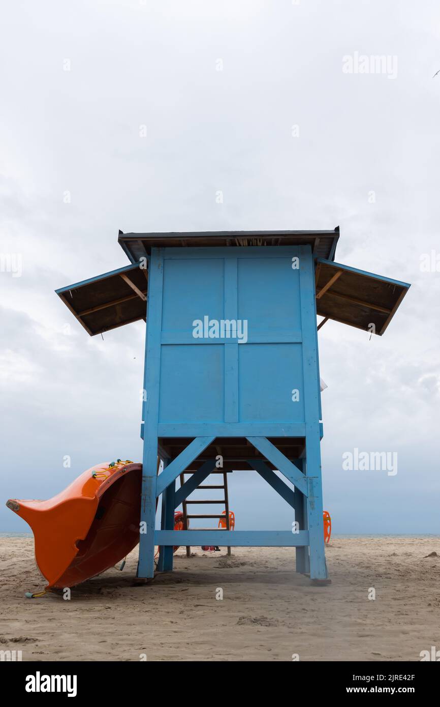 A blue lifeguard booth on the beach on a cloudy day. Orange lifeboat ...