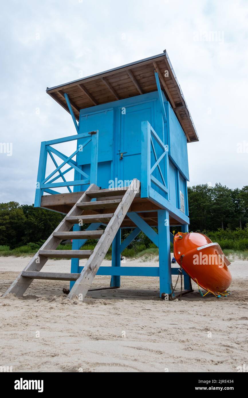 A blue lifeguard booth on the beach on a cloudy day. Orange lifeboat ...