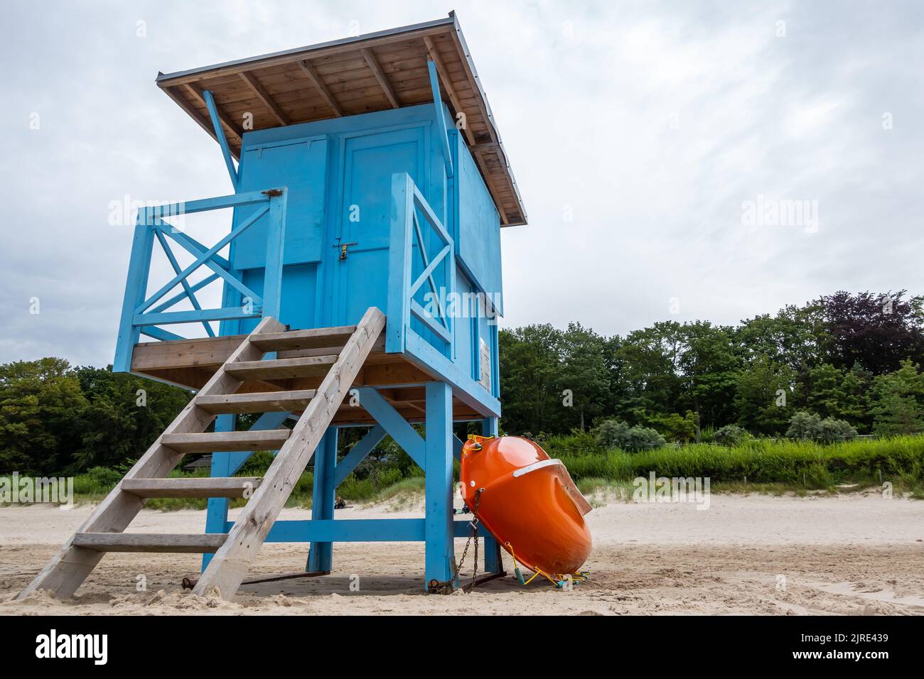 A blue lifeguard booth on the beach on a cloudy day. Orange lifeboat ...