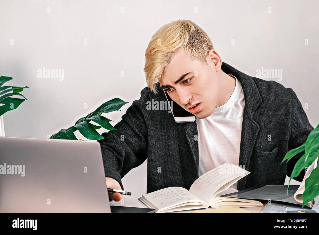 Young, frustrated, shocked man holds on to his head staring at a laptop ...