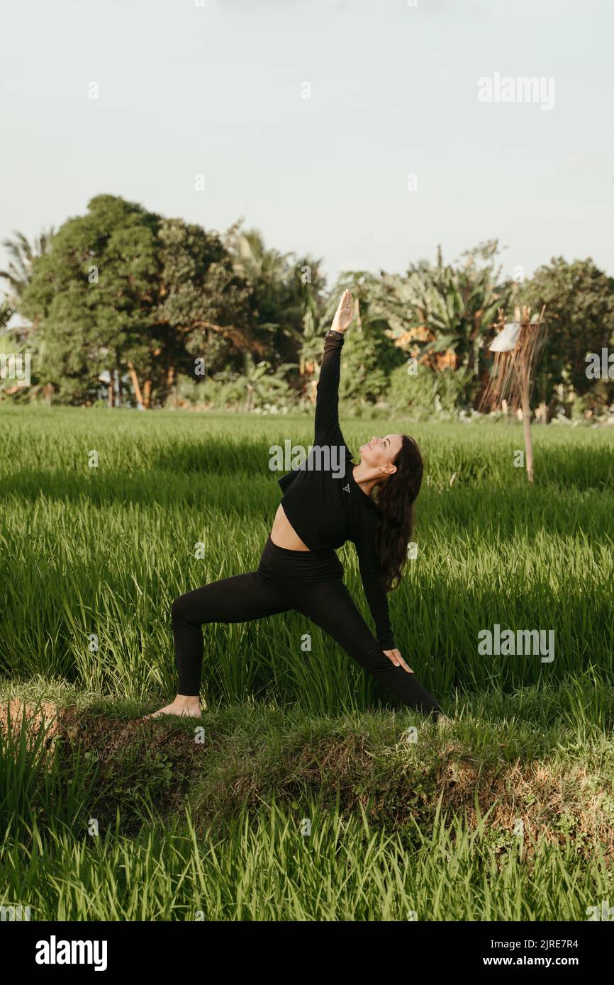 Photo of beautiful woman in black sportive suit practicing yoga in Bali ...