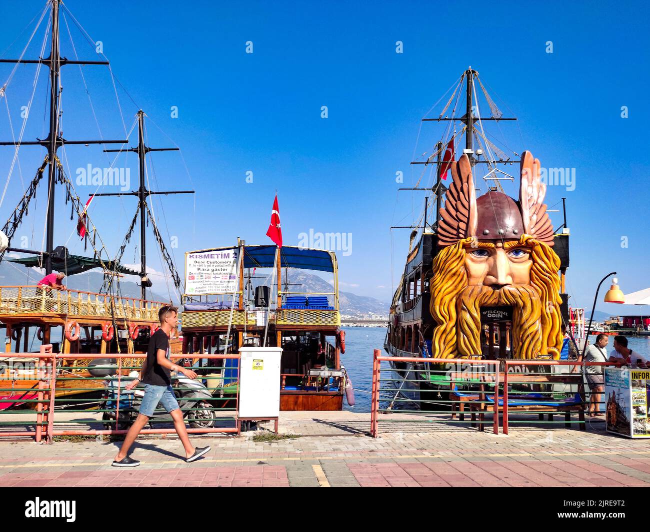 A man is walking in the harbor area in Alanya. A huge ship with a ...