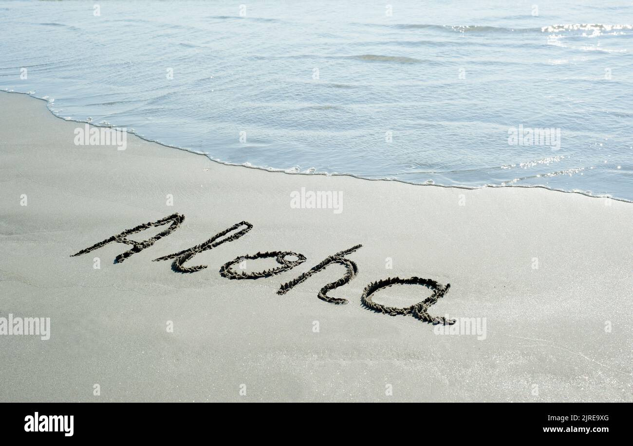 Concept or conceptual Aloha text handwritten in sand on a beach with ...