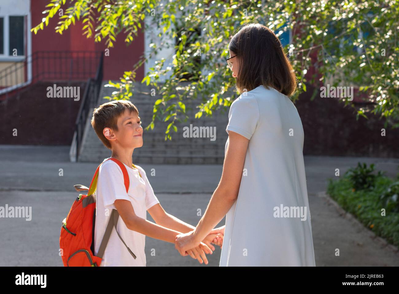 Mother and child boy with a school backpack on the street near the ...