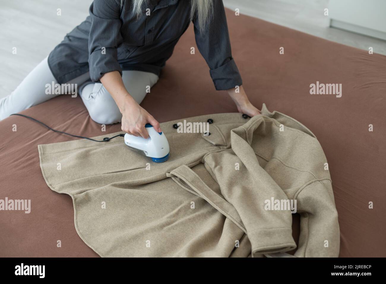 woman uses a machine for removing pellet and spools from clothes and ...