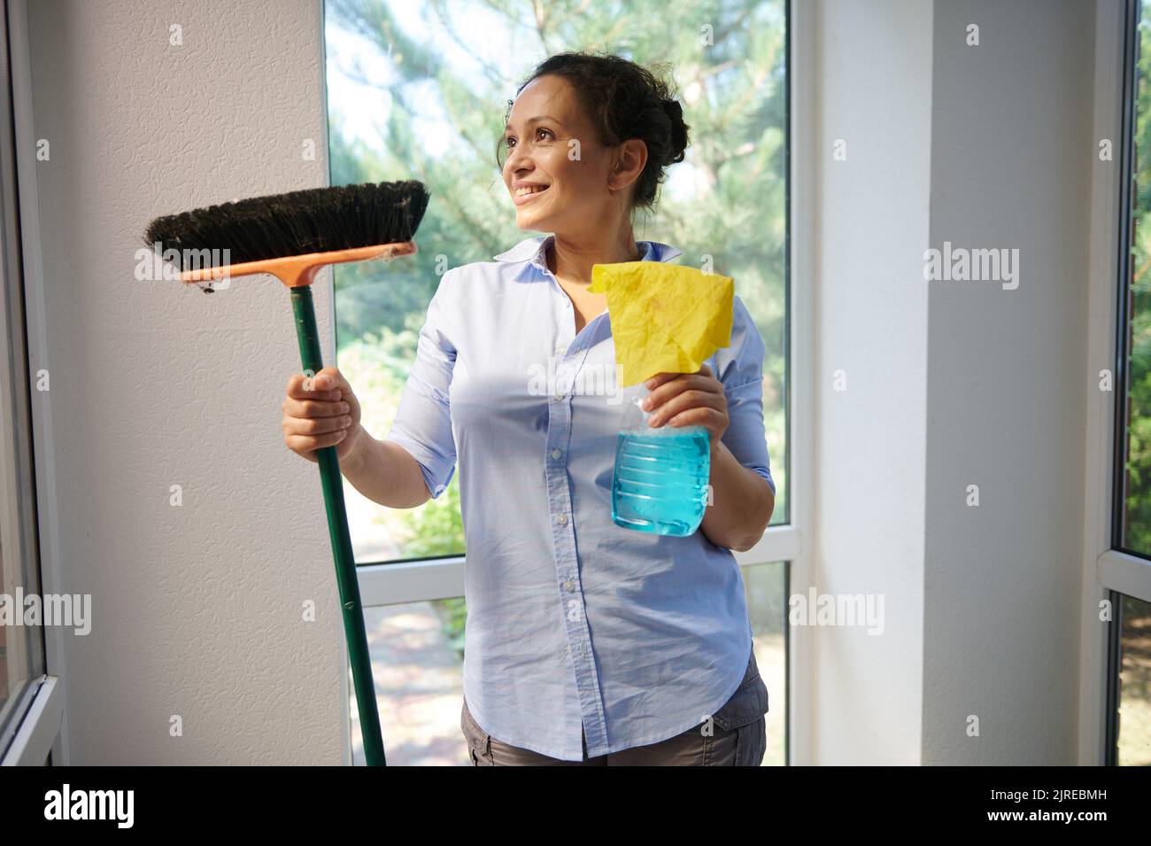 Charming woman, a homemaker, maid, housewife holding a broom and ...