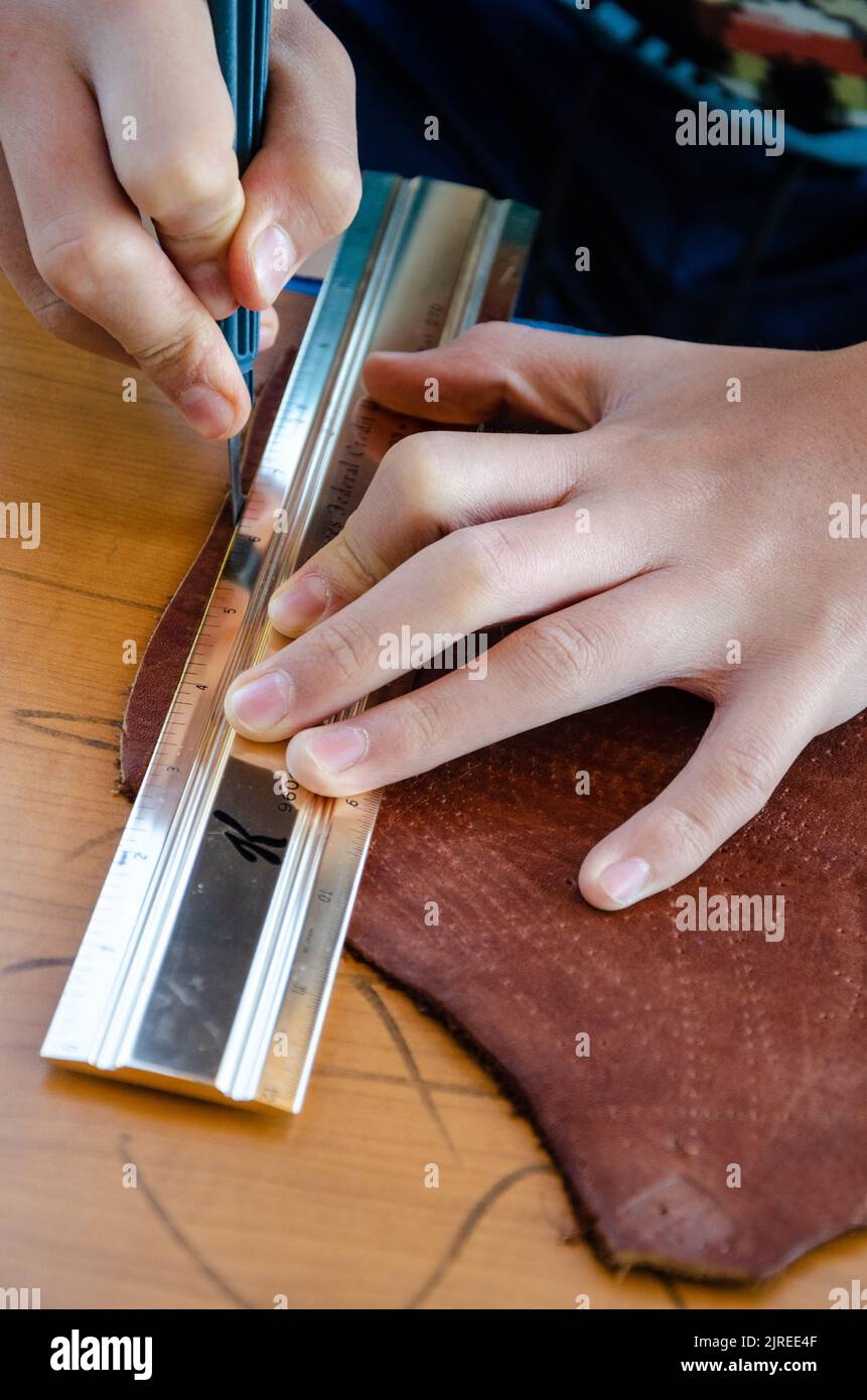Close up view of a teenager's hands using a sharp scalpel and metal ...