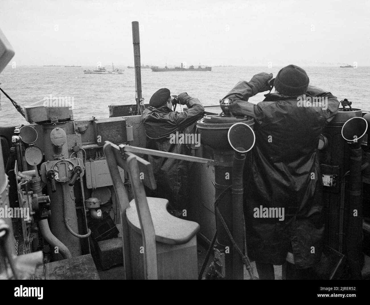 Officers on the bridge of a destroyer, escorting a large convoy of ...