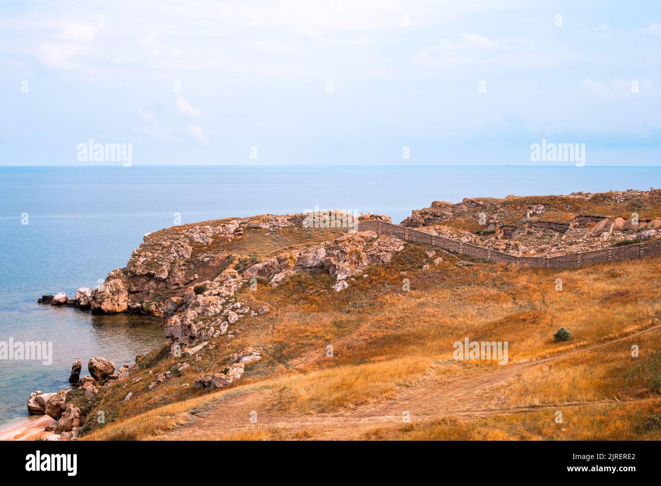 Sea rocky coast with mountains and a long stone fence. Travel and ...