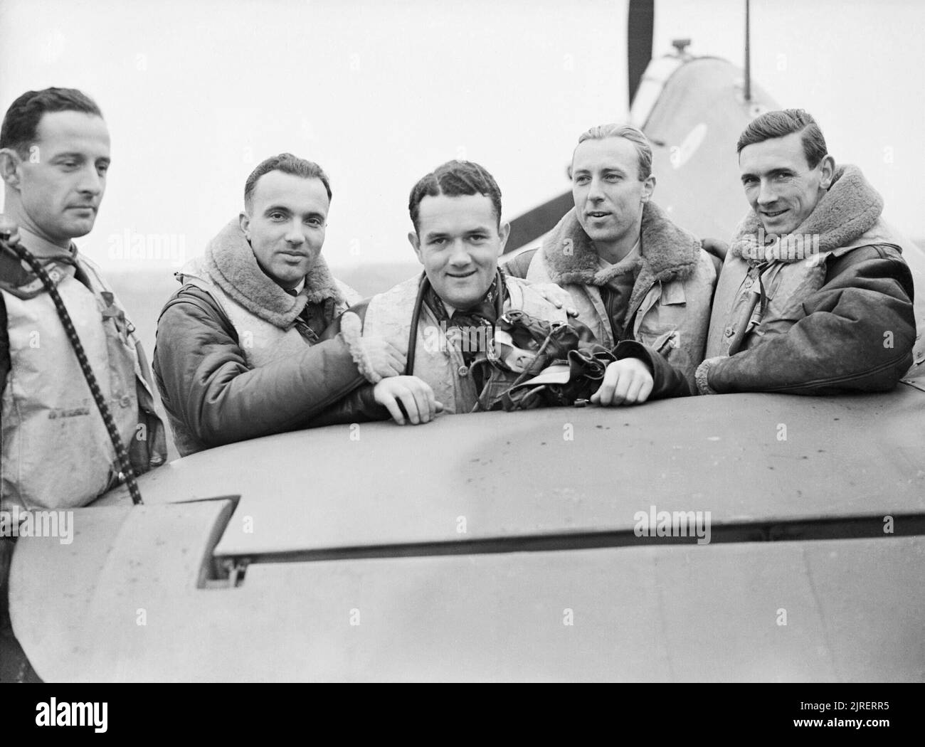 Pilots of No. 303 (Polish) Squadron RAF stand by the tail of one of ...