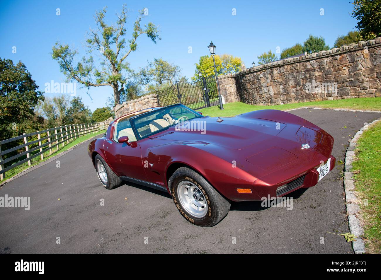 Chevrolet Corvette Stingray Parked On A Fence Lined Lane To A Farm On A Sunny Day With A Stone