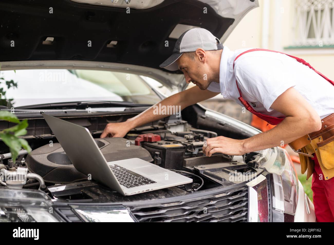 Mechanic man close up using laptop computer examining tuning fixing ...