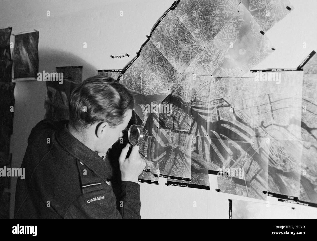 A Canadian photographic reconnaissance pilot examining a mosaic of ...