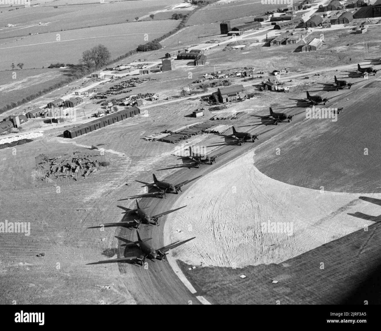 Douglas Dakotas of No. 233 Squadron RAF lined up on the perimeter track ...