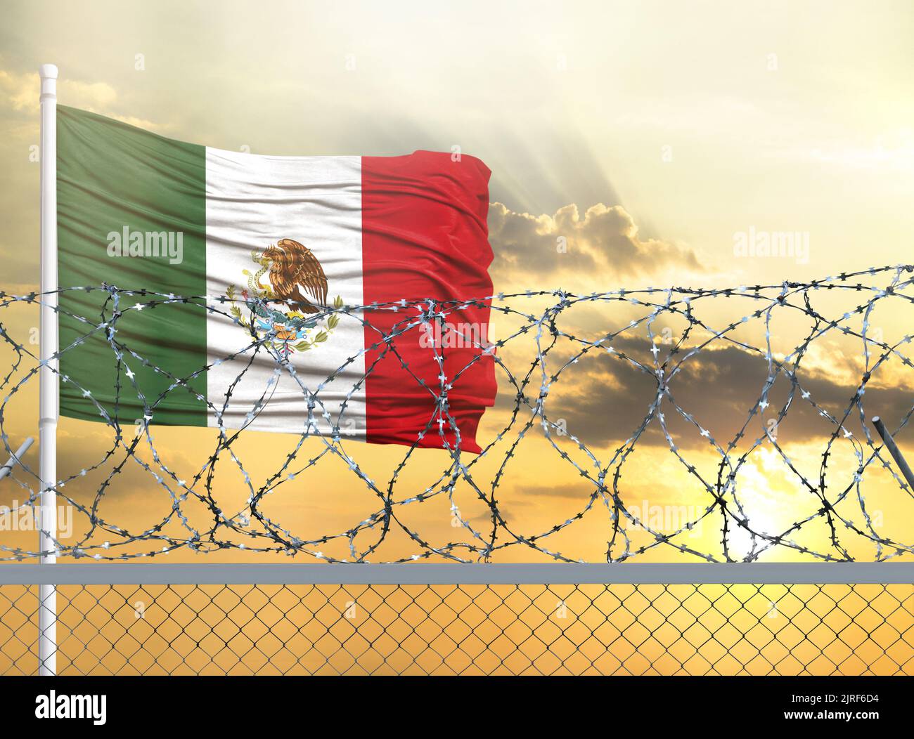 Flagpole with the flag of Mexico against the sky and behind a fence ...