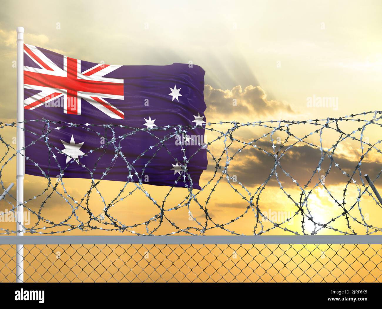 Flagpole with the flag of Australia against the sky and behind a fence ...