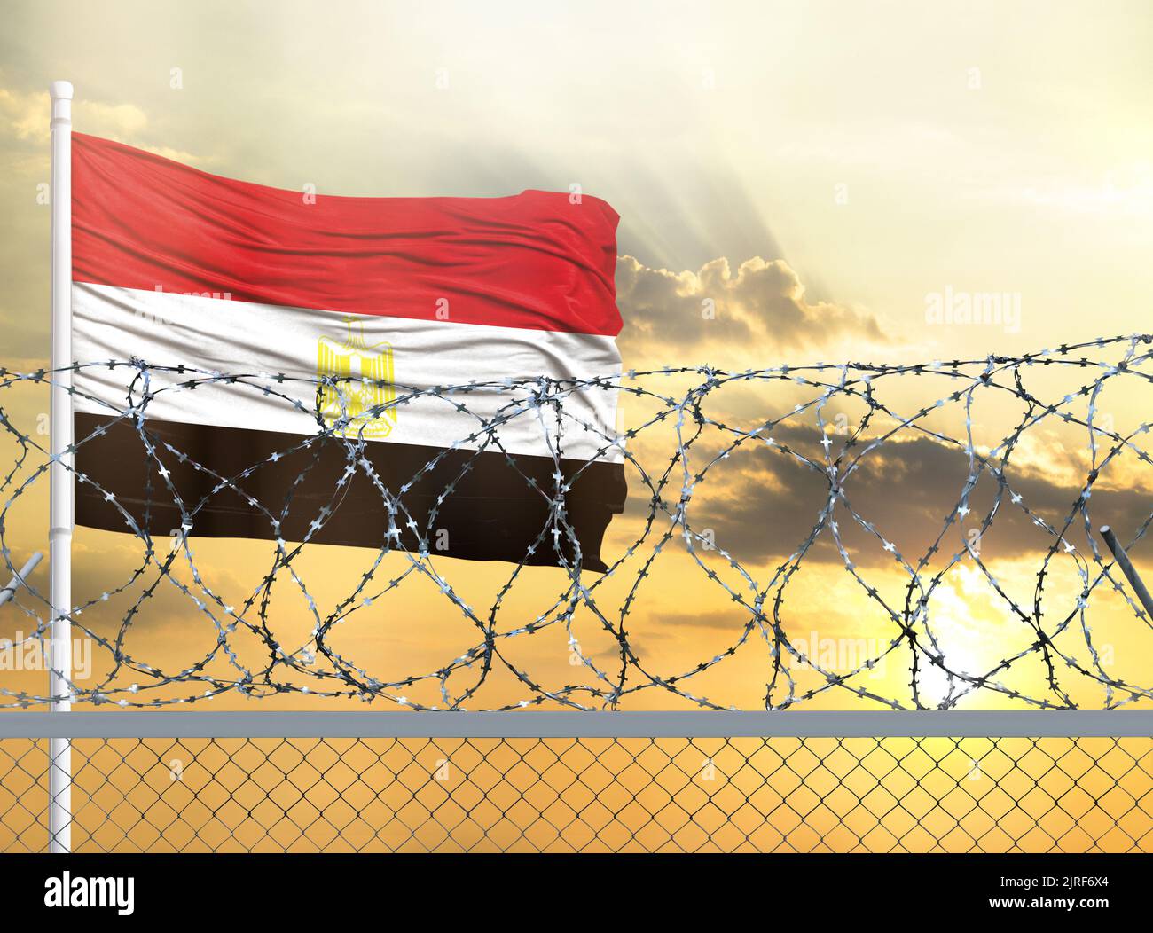 Flagpole with the flag of Egypt against the sky and behind a fence with ...
