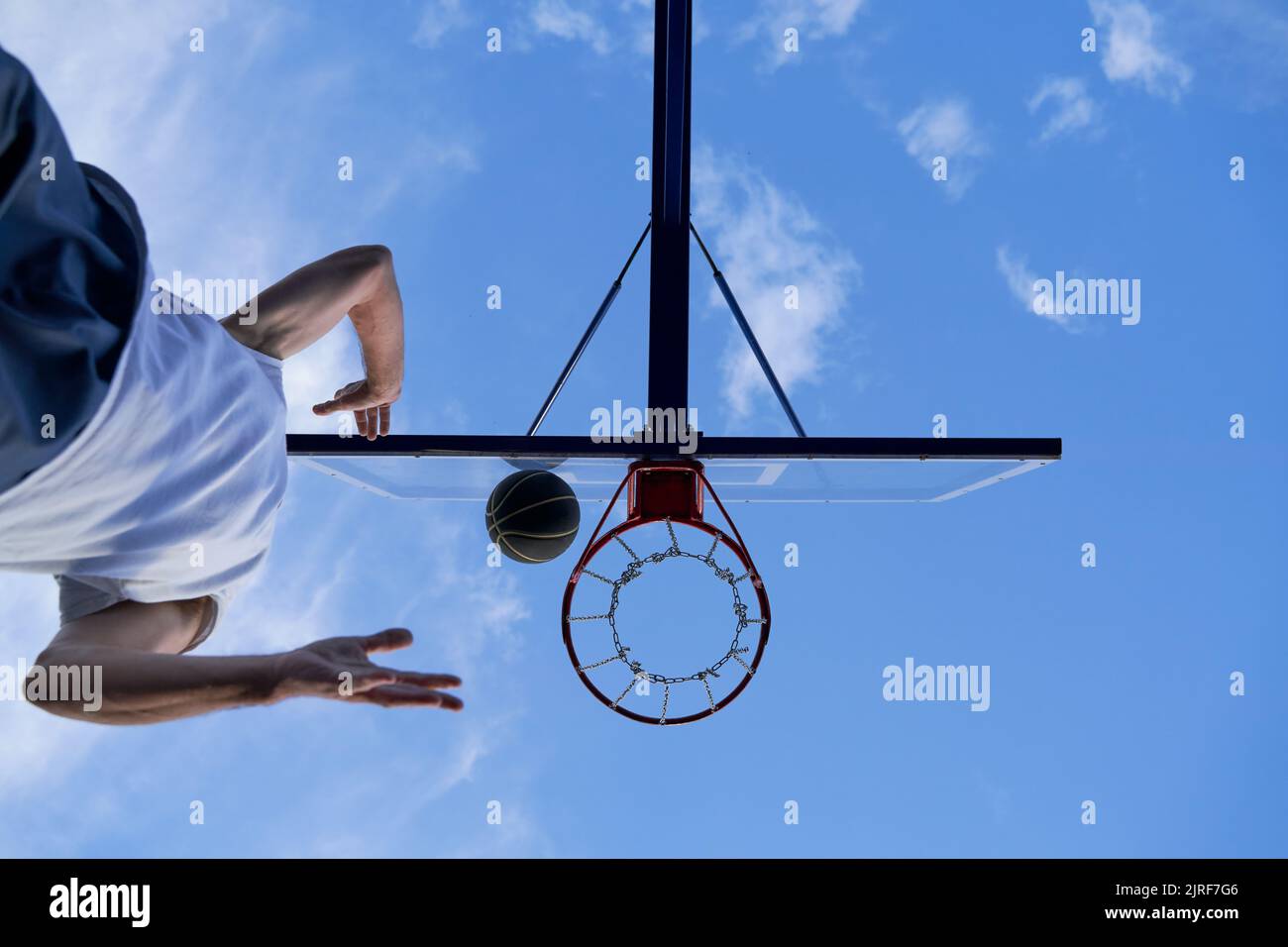 Man is training basketball on the street court. He throw ball to the ...
