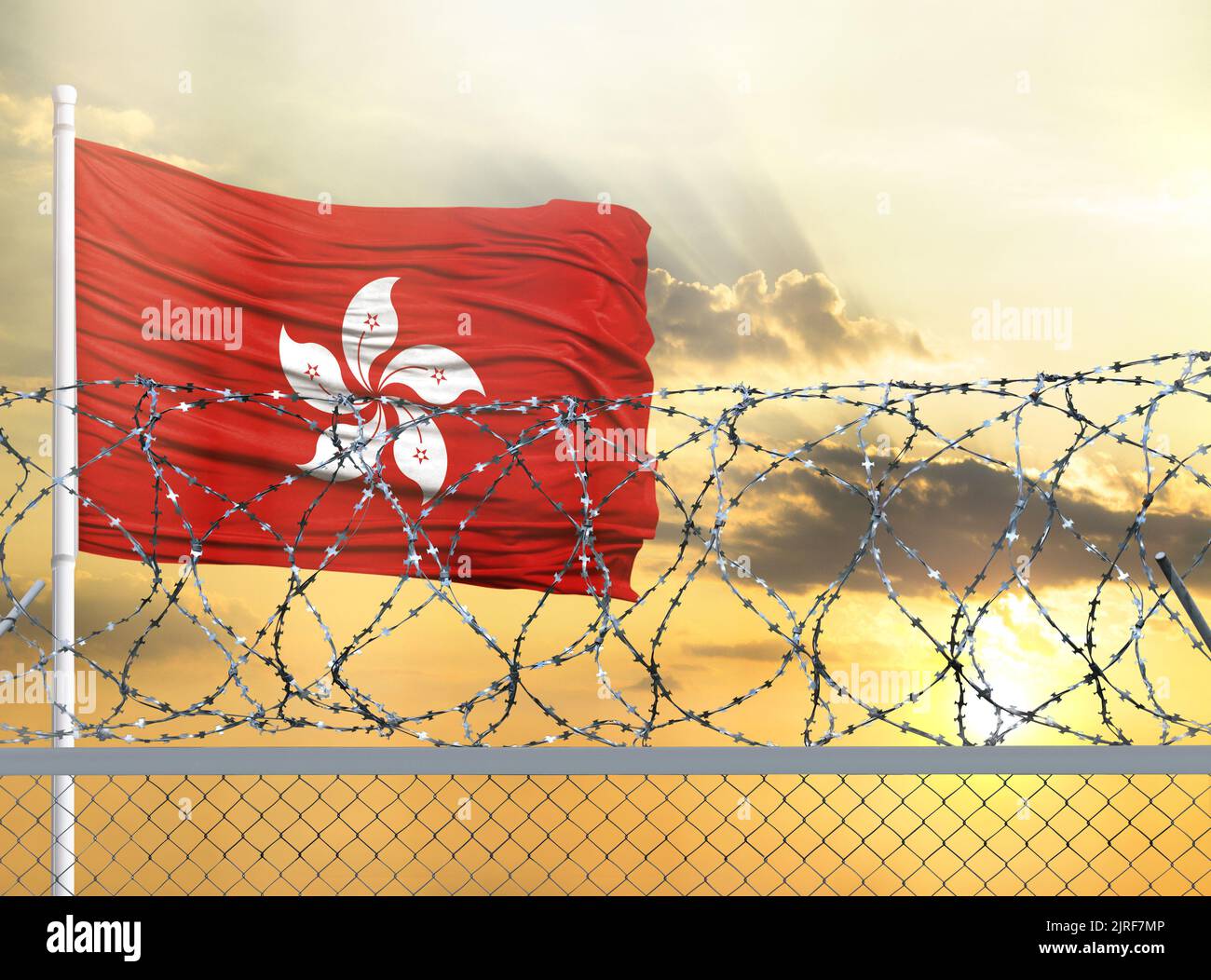 Flagpole with the flag of Hong Kong against the sky and behind a fence ...