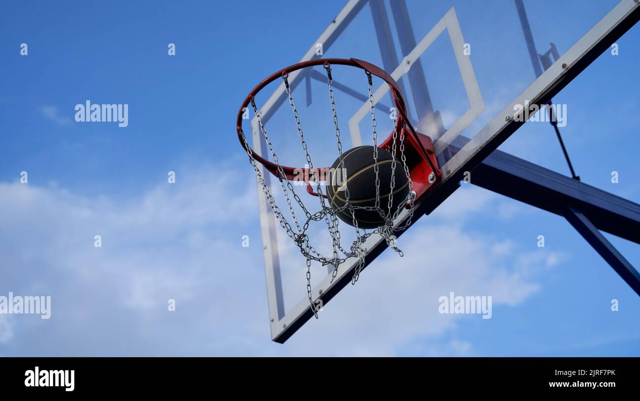 Street basketball ball falling into the hoop. Close up of black ball in ...