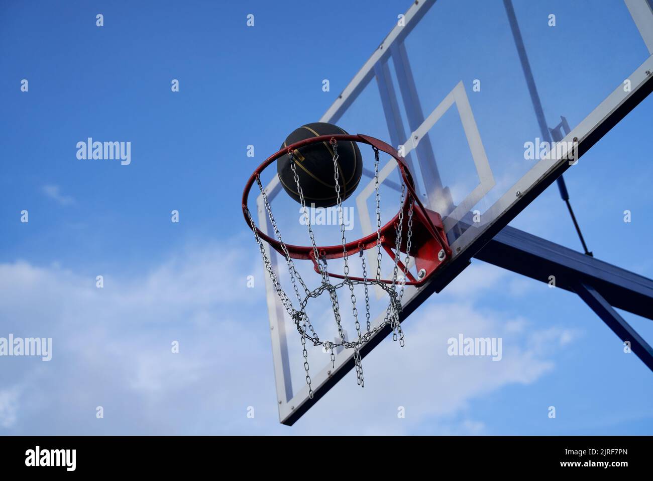 Street basketball ball falling into the hoop. Close up of black ball ...