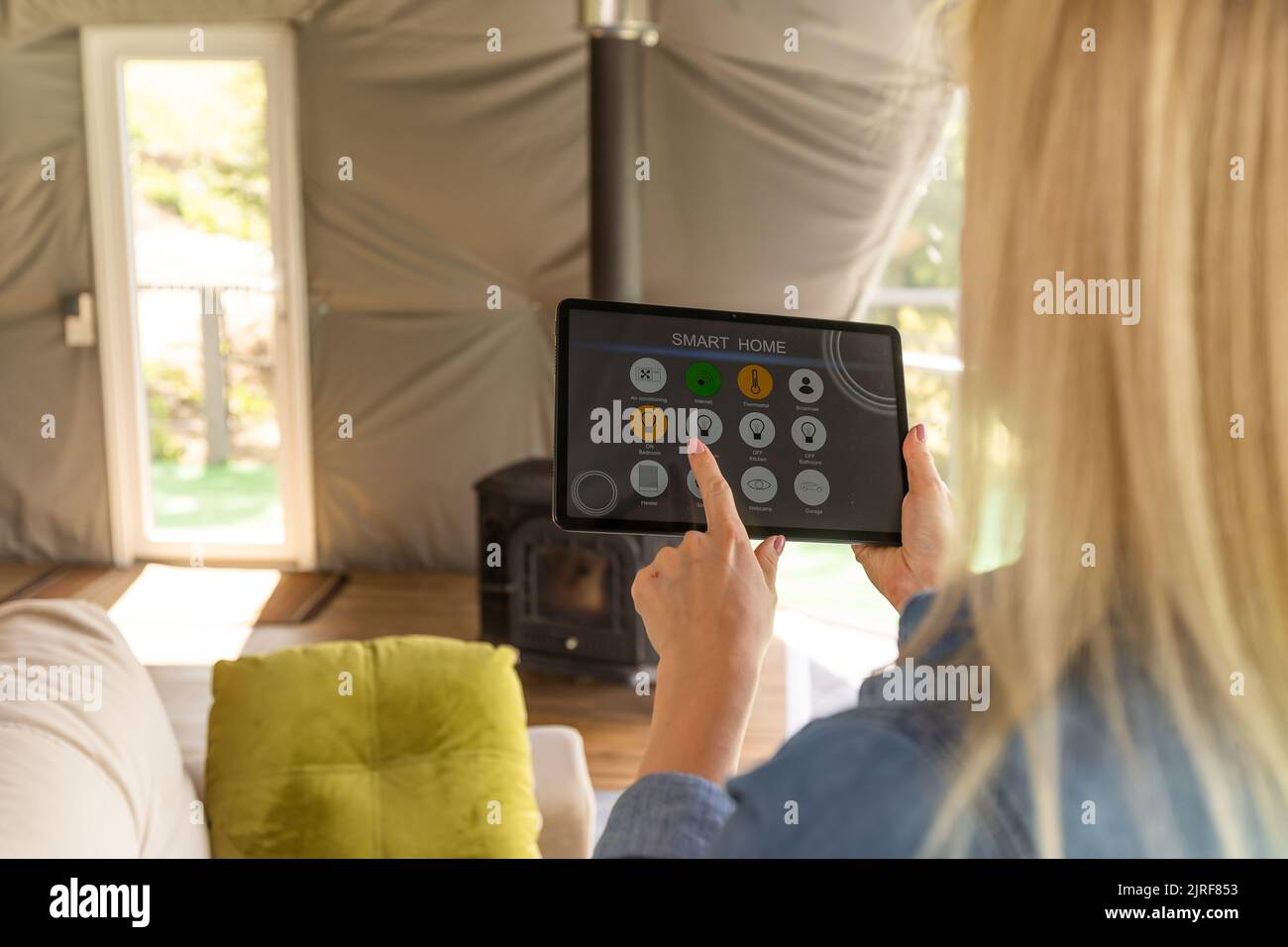 hands holding smart tablet with app smart home on .home living room as ...