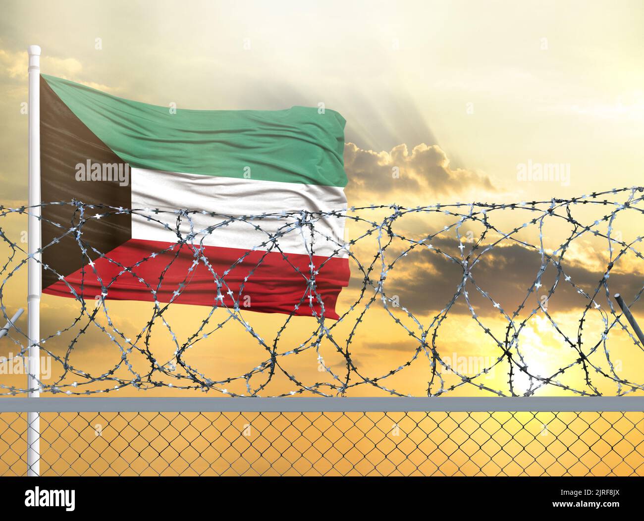 Flagpole with the flag of Kuwait against the sky and behind a fence ...
