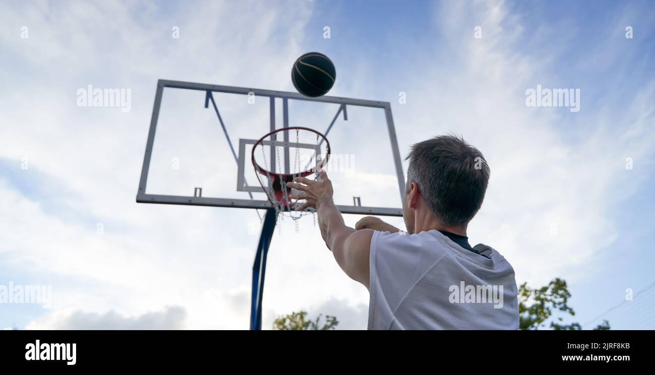 Man is throwing ball to the hoop. Training of basketball on the street ...