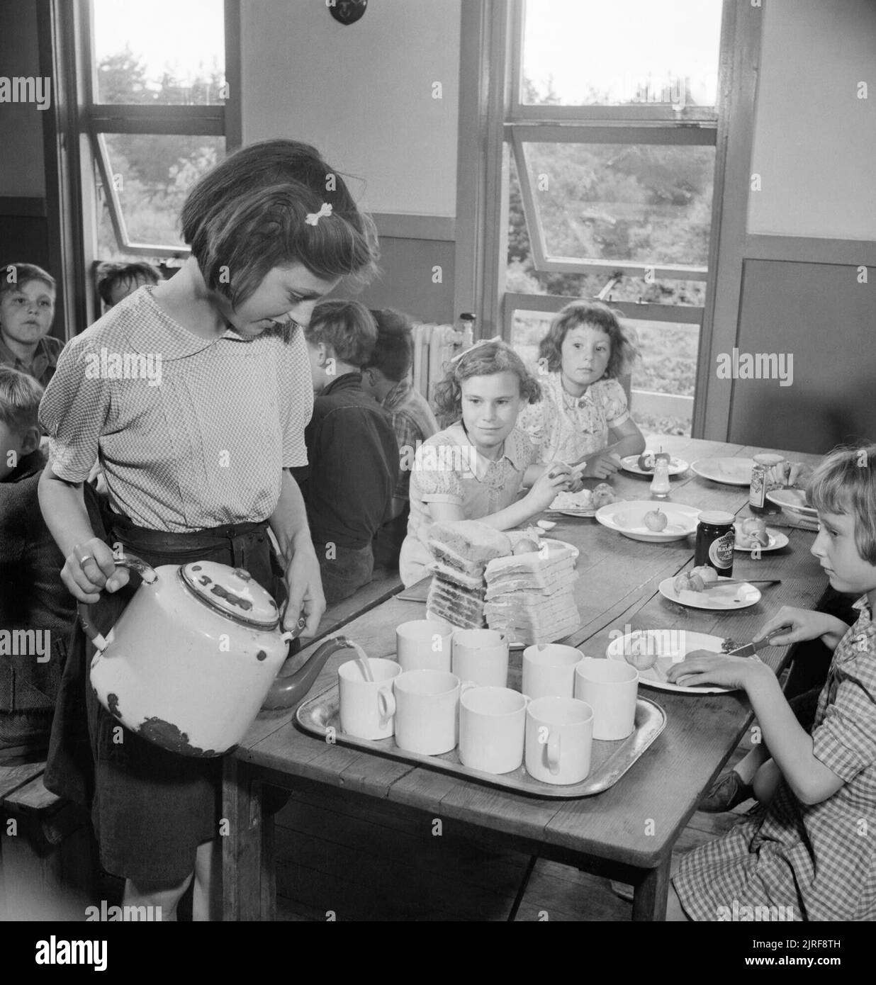 June Beale pours tea for other evacuee children in the dining hall at ...