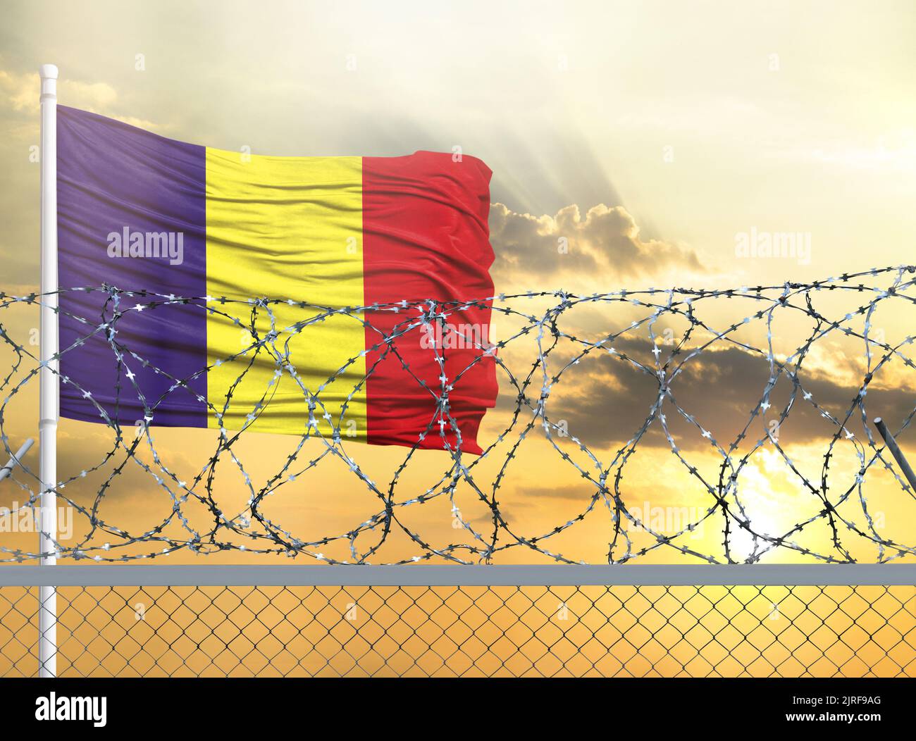 Flagpole with the flag of Romania against the sky and behind a fence ...