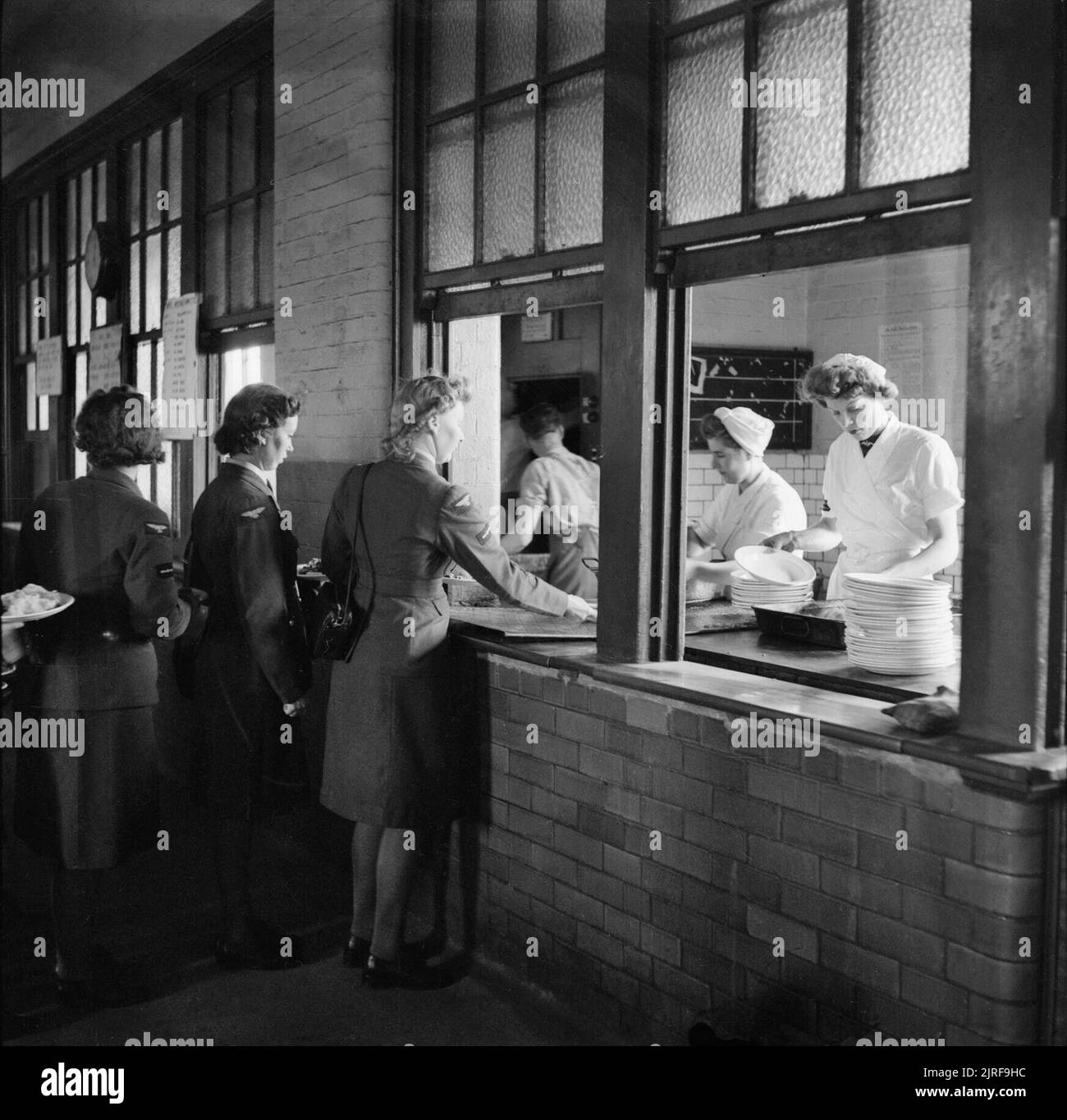 Members of the Women's Auxiliary Air Force catering section serve meals ...