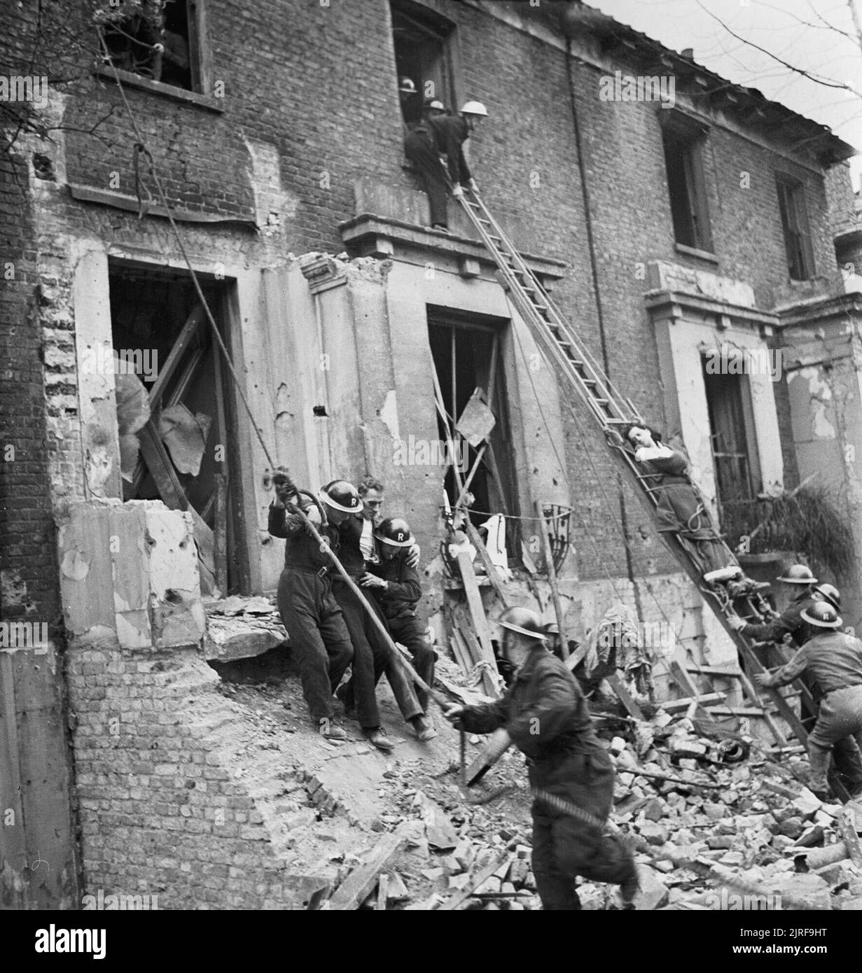 Members of a heavy rescue party evacuate civilians from a bomb damaged ...