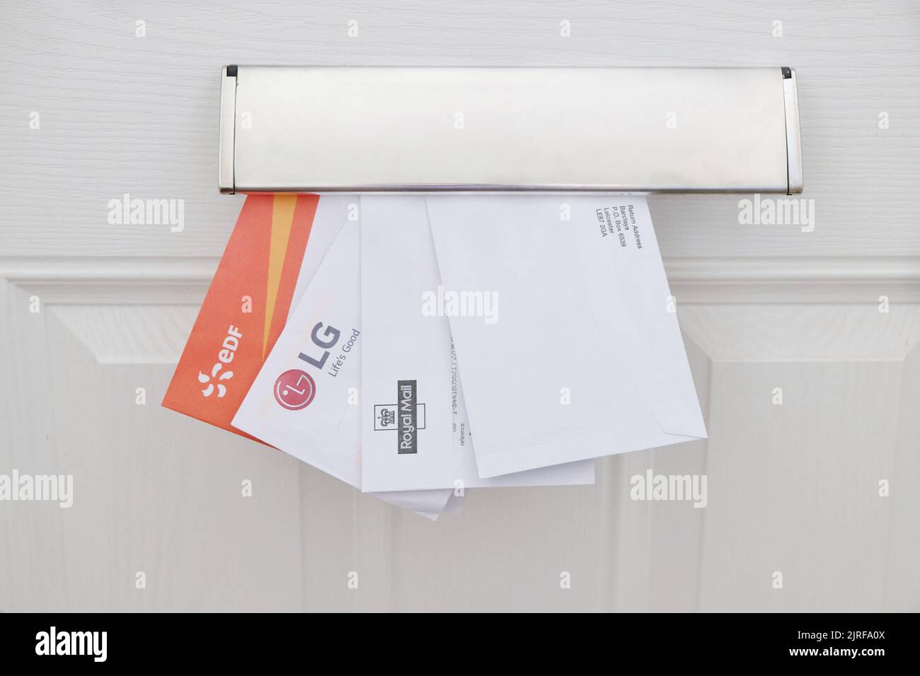 London, UK. A selection of delivered letters hang down from a letterbox ...