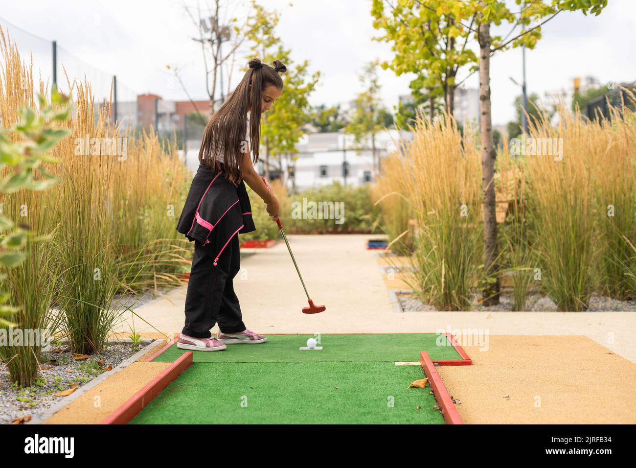 Miniature golf outdoor. Little caucasian girl golfing in the mini golf ...