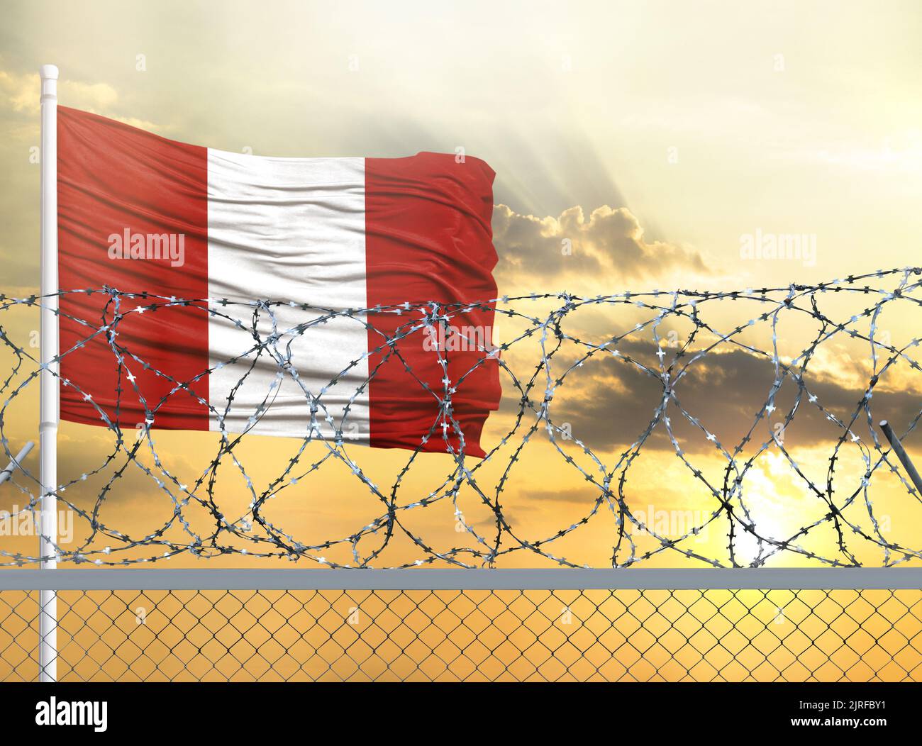 Flagpole with the flag of Peru against the sky and behind a fence with ...