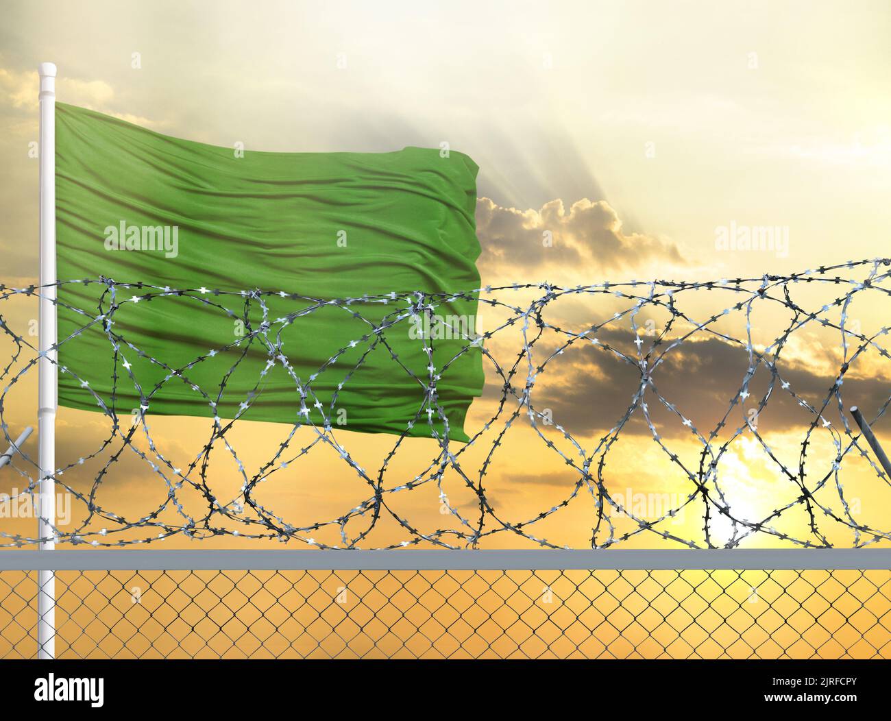Flagpole with the flag of Libya against the sky and behind a fence with ...
