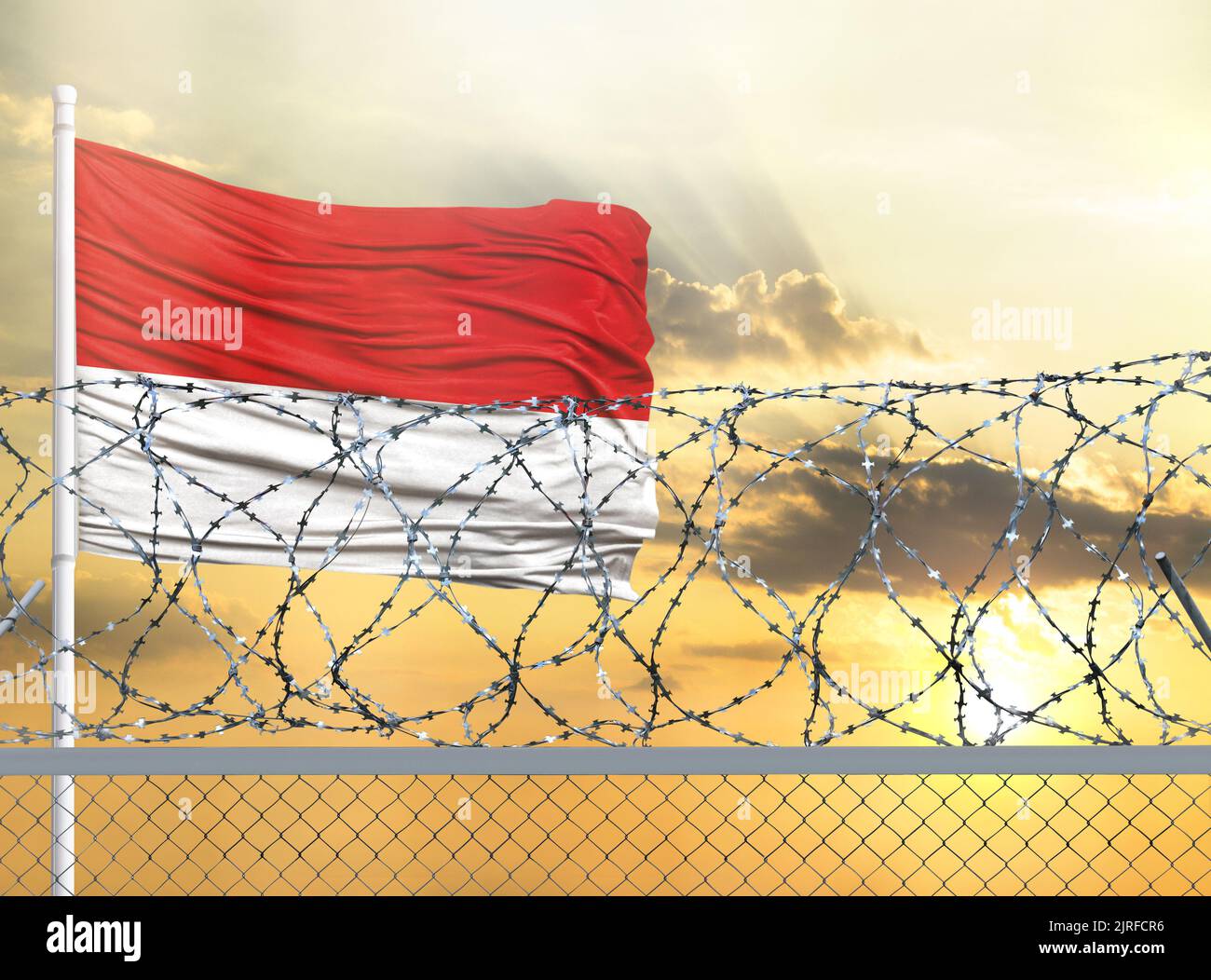 Flagpole with the flag of Monaco against the sky and behind a fence ...