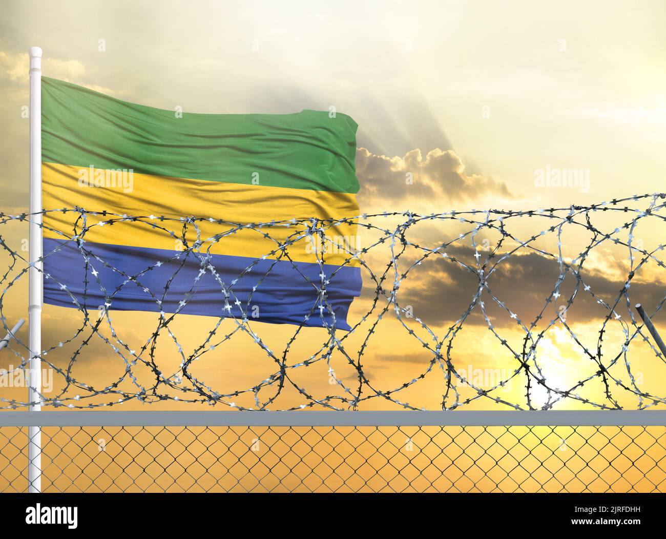 Flagpole with the flag of Gabon against the sky and behind a fence with ...